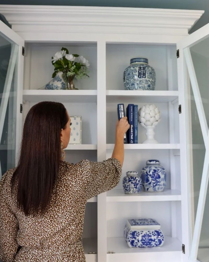 Woman_placing_styling_items_into_a_white_bookcase_in_a_hamptons_style ...